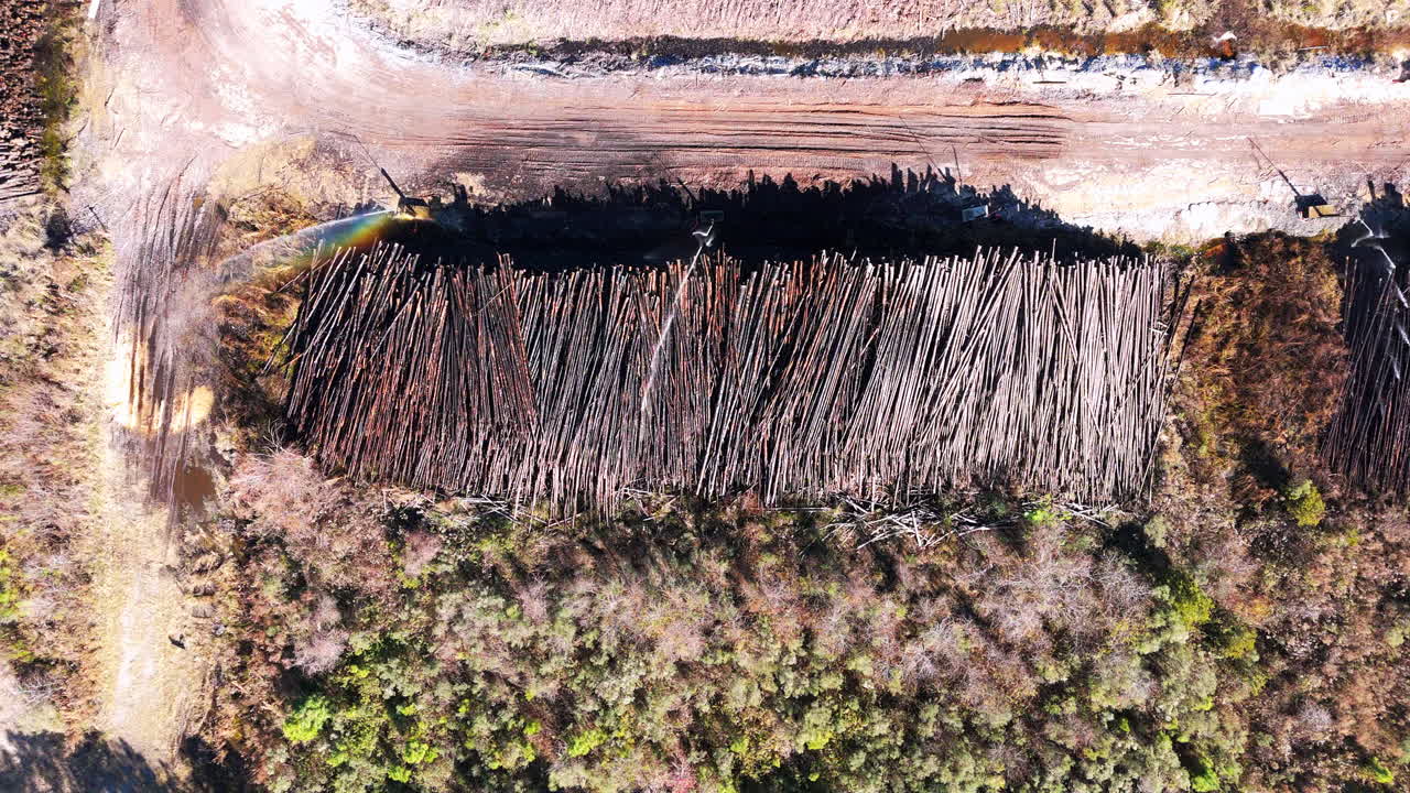 Top Down Aerial Footage Of A Water Sprinkler Over A Large Pile Of Logs ...