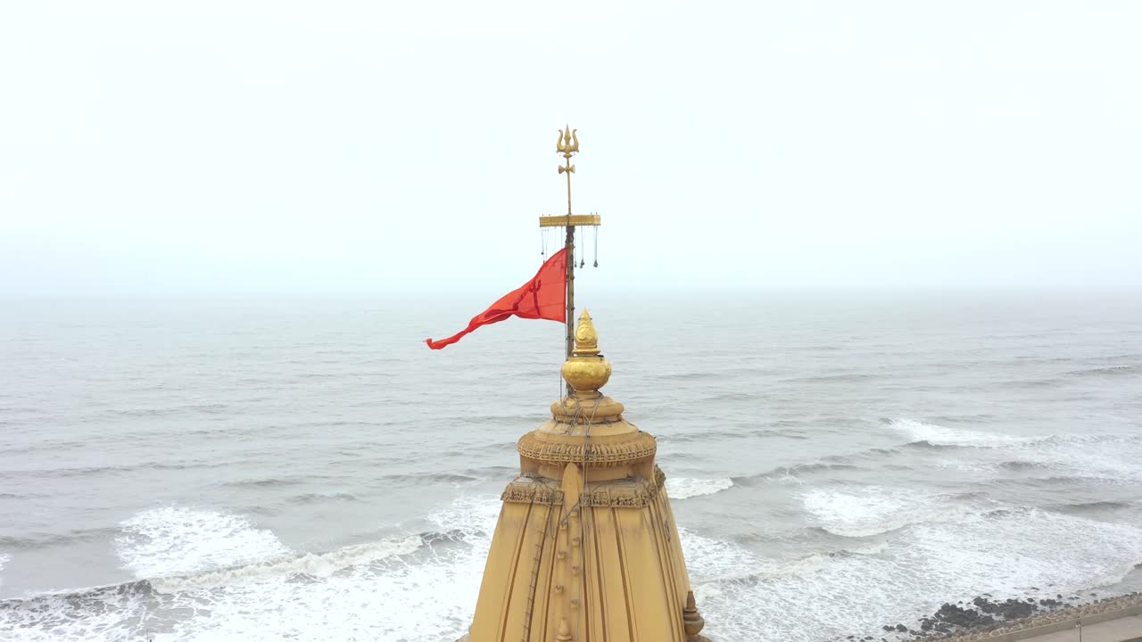 Aerial Backward Moving Shot Of Saffron-colored Hindu Flag Flying On Top ...