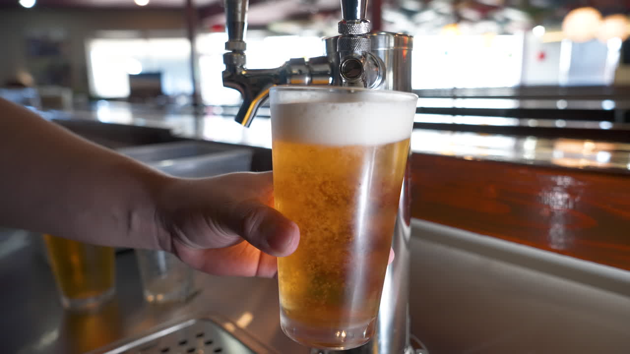 Premium stock video - Bartender pulls a perfect pint from a stainless ...