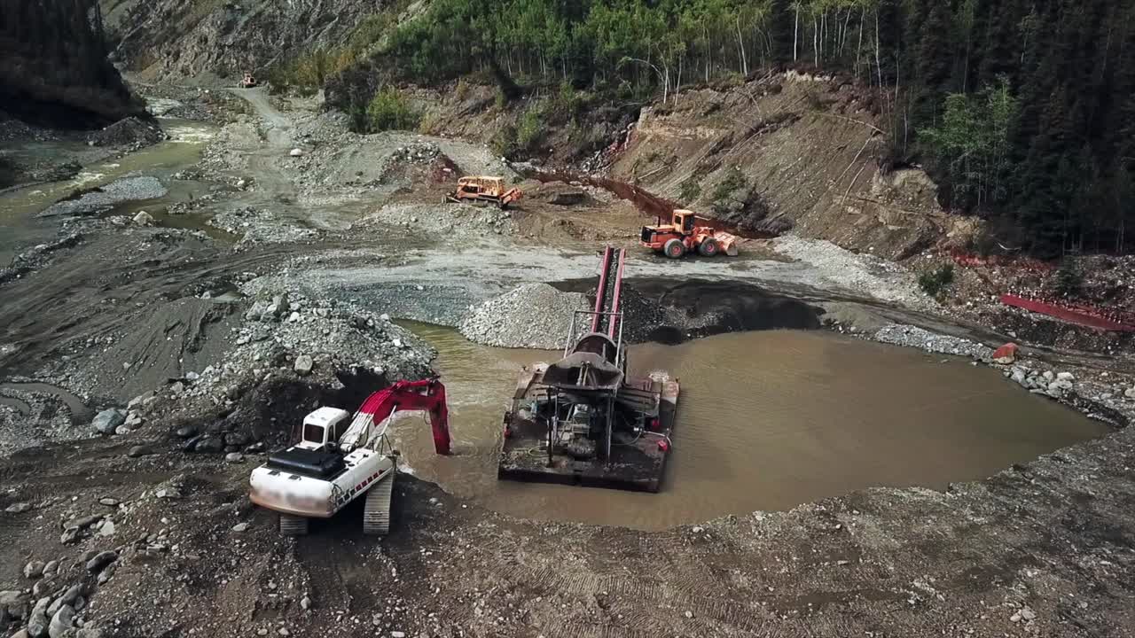 Premium stock video - Excavator feeding pay dirt into floating sluice ...