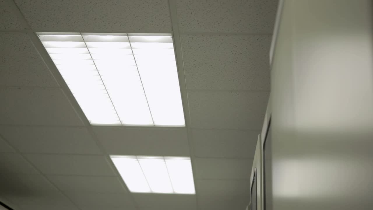 Fluorescent Lights Flicker On In A Dim, Textured Ceiling Office Space ...