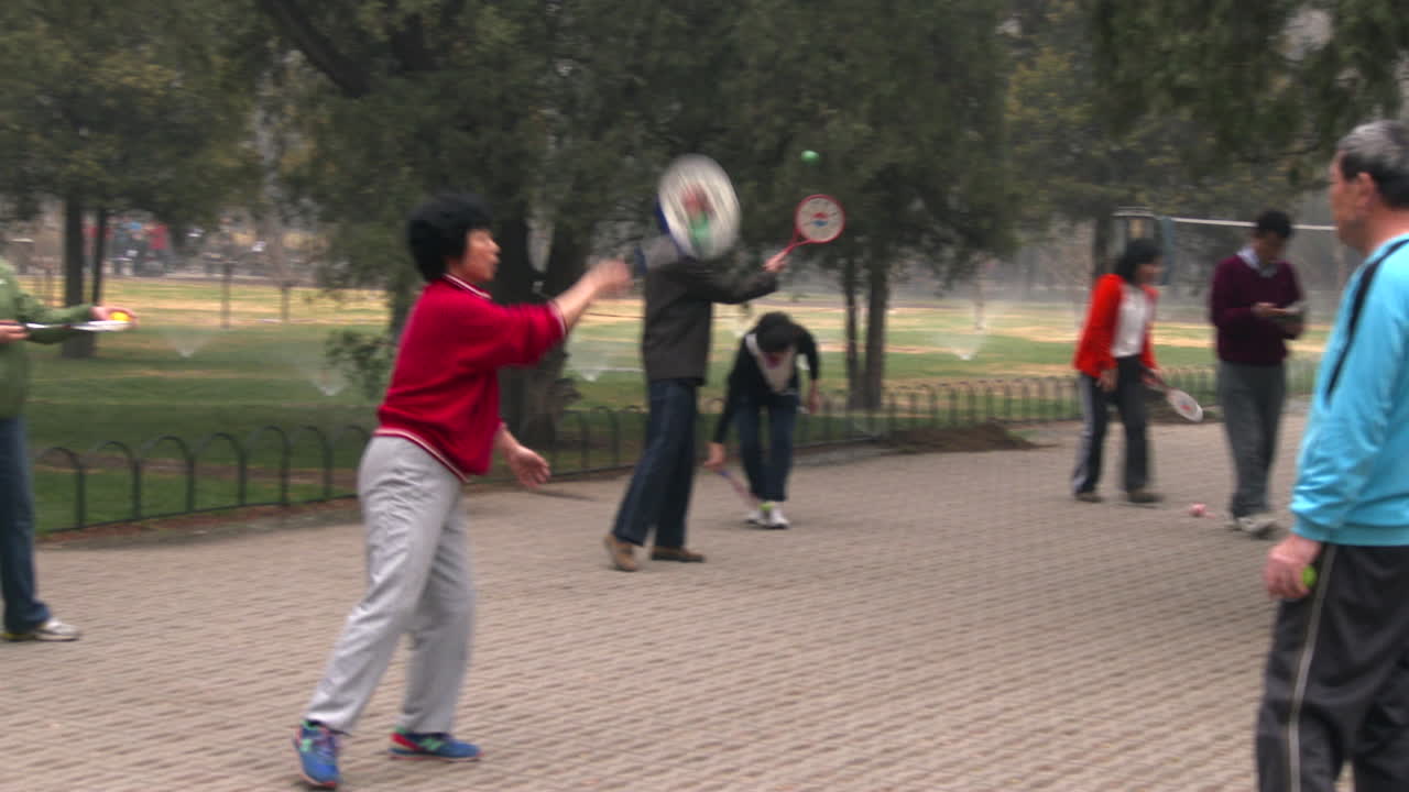 People In A Park In China Play An Exercise Game With A Ball And Paddle ...