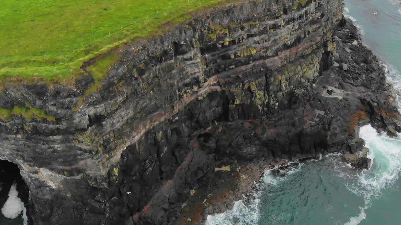 Tilted Top Down Aerial View Of Oceanic Waves Hitting A Steep Cliff ...