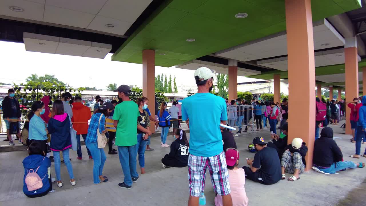Premium stock video - Panning shot of a crowded queue wearing a mask