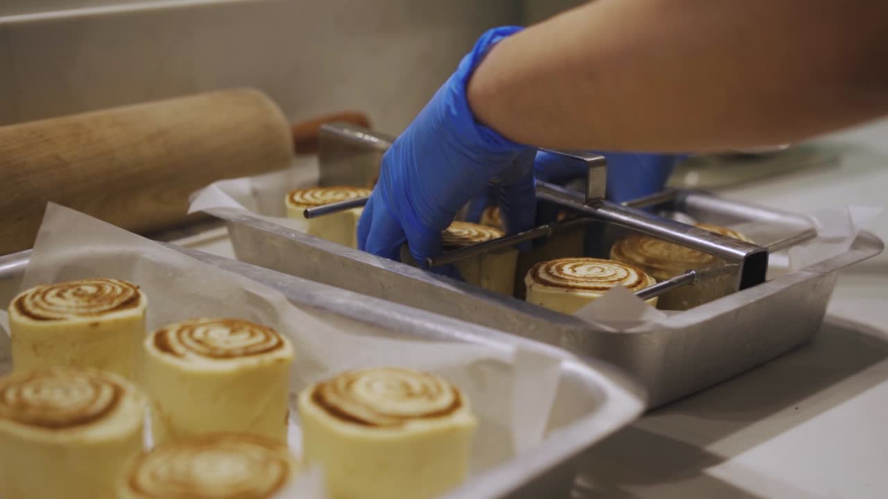 Premium stock video - Placing cinnamon rolls in a tray lined with ...