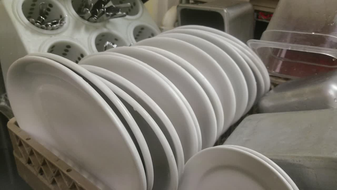 Premium stock video - Clean and shiny dishes dry on a rack in front of ...
