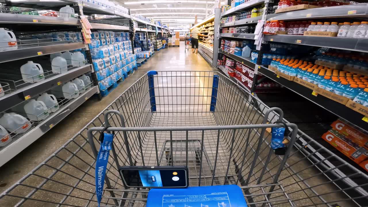POV While Pushing A Cart Through Walmart Past Shelves Of Water And Past ...