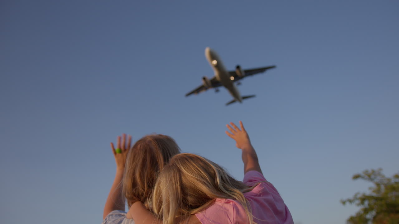 Two little girls waving goodbye to a plane Premium Stock Video Footage