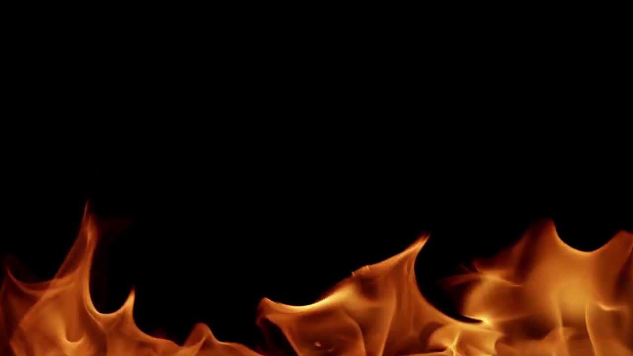 Intense orange fire flames burn and flicker along the bottom of a black ...