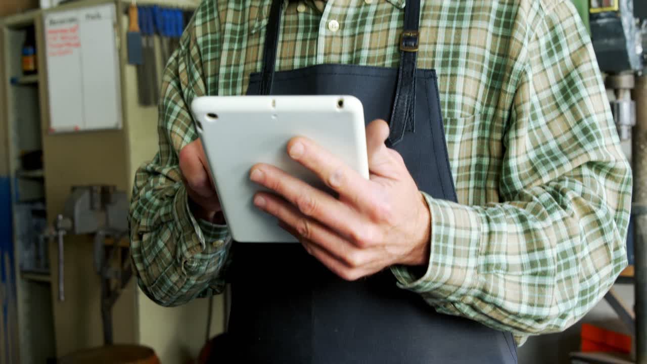 Premium stock video - Craftsman using digital tablet 4k