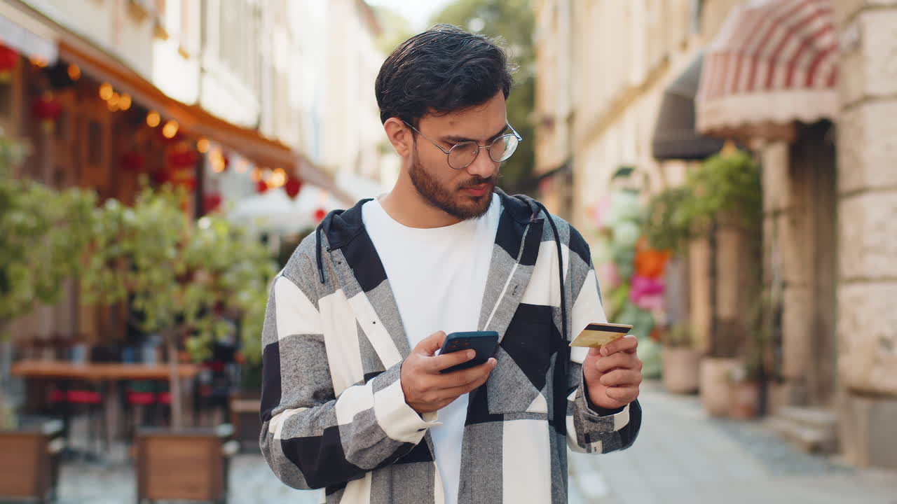 Smiling young man using credit card smartphone while transferring money ...
