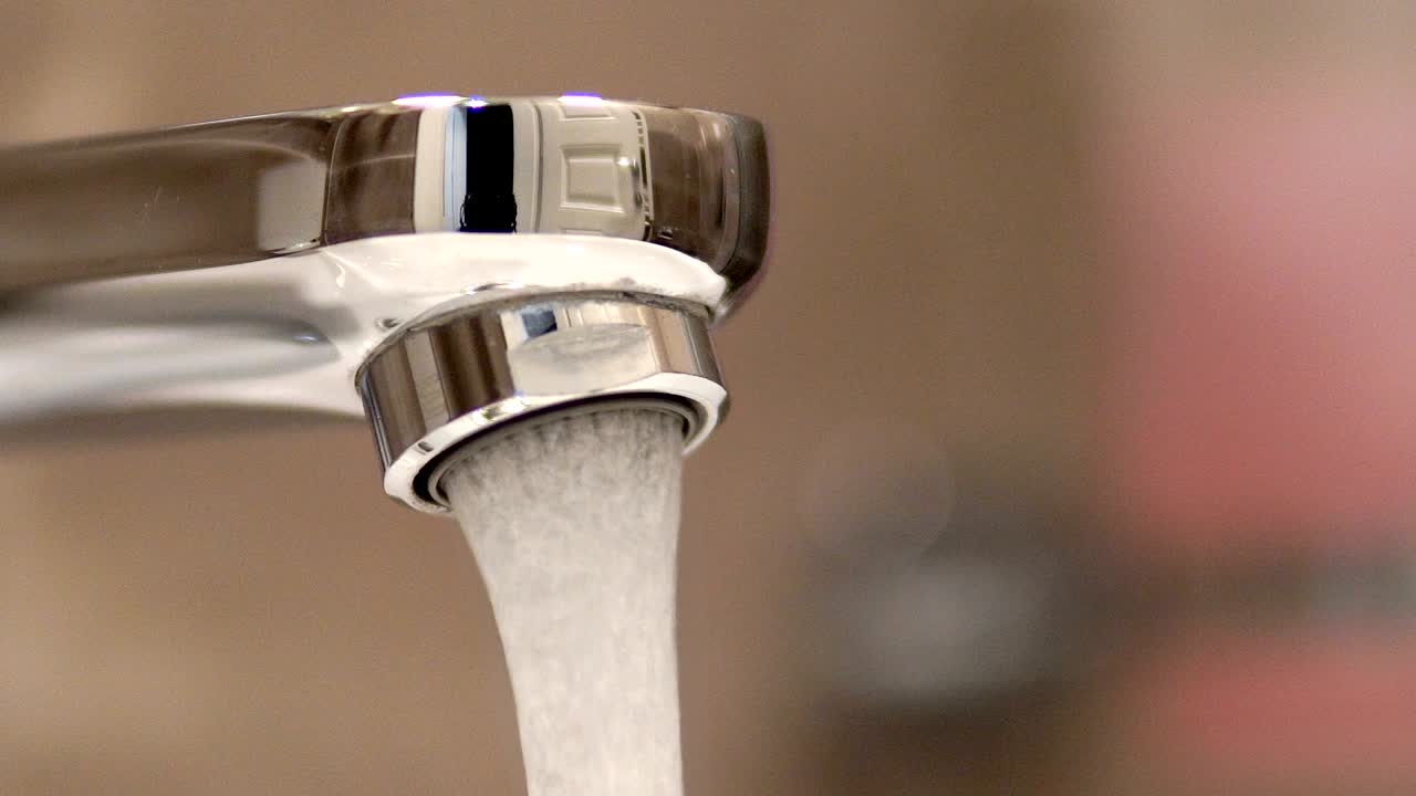 Open chrome faucet washbasin, water flow loop background, cinematic dof ...