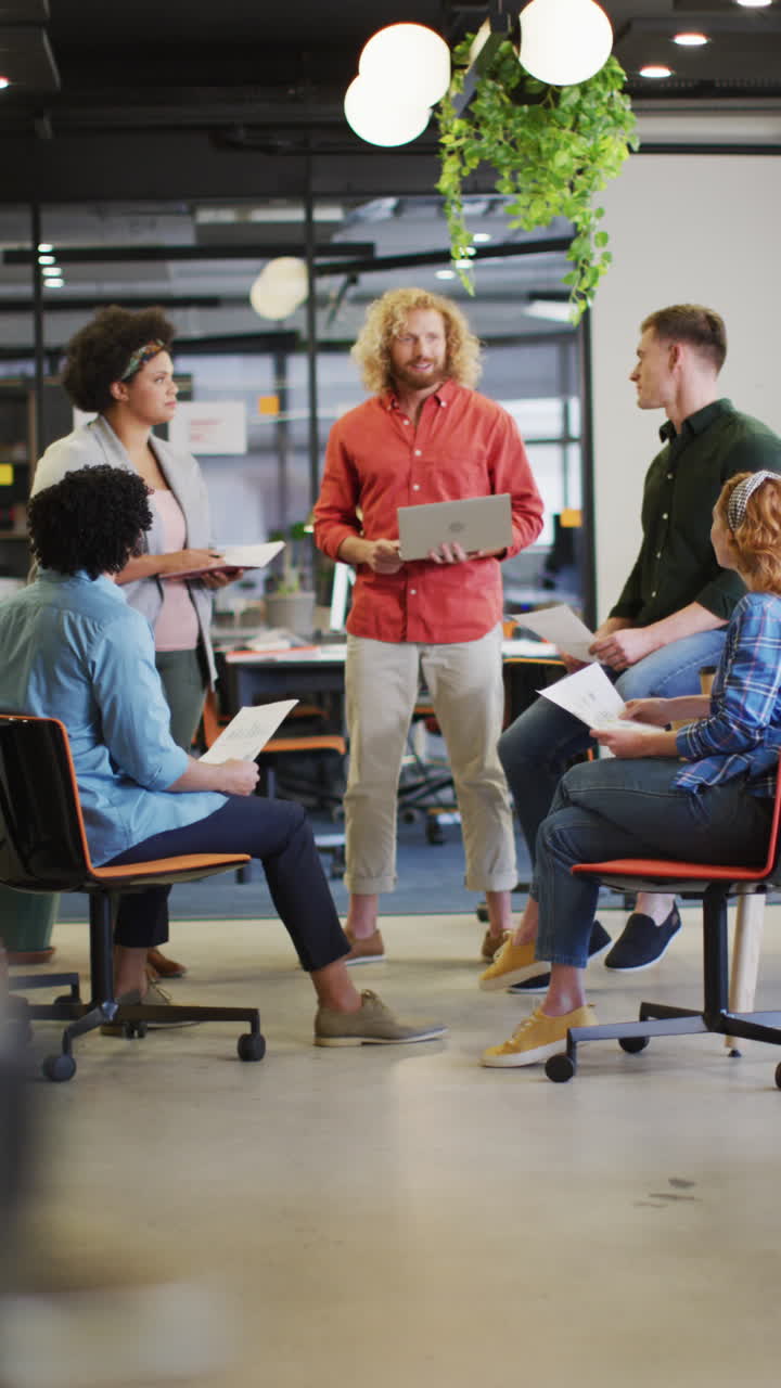 Vertical video of diverse business people discussing work during ...