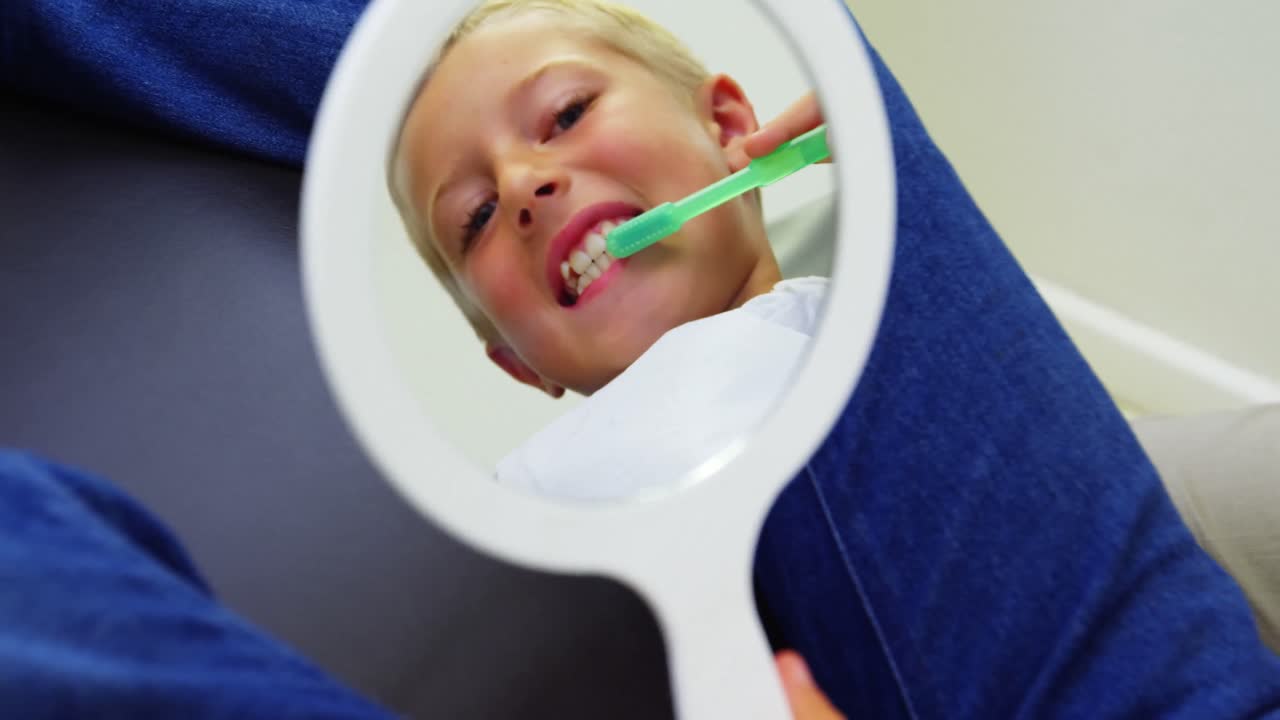 Premium stock video - Dentist brushing a young patients teeth