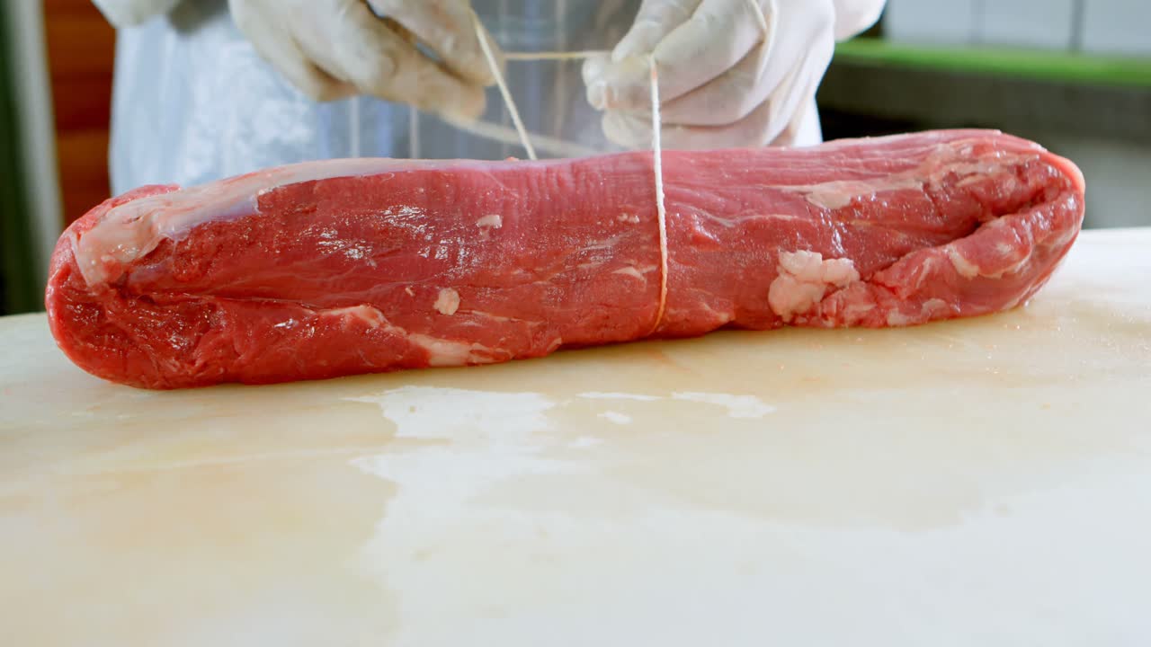 Butcher tying meat with thread in shop 4k Premium Stock Video Footage