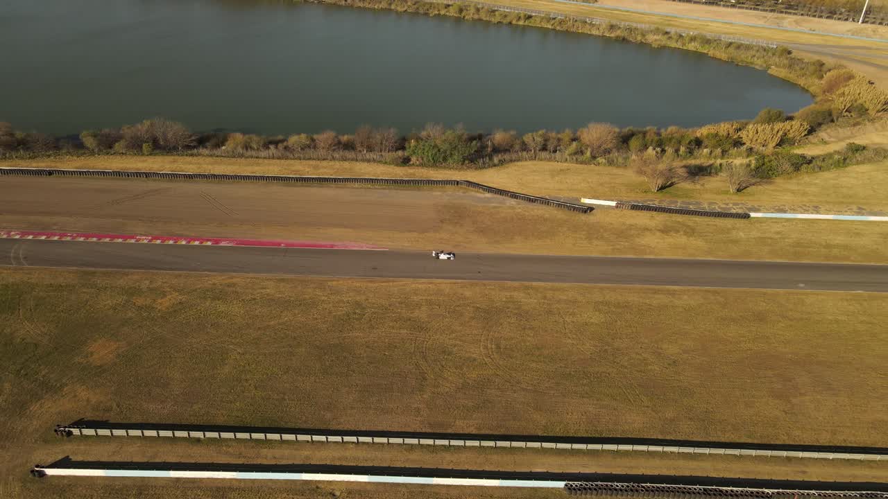 Premium stock video - Aerial view following white car on racetrack straight