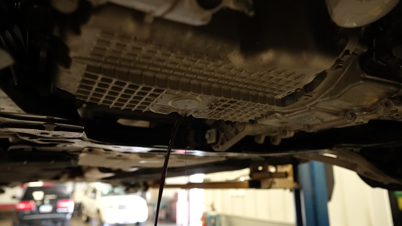 Premium stock video - Draining motor oil out of car engine, panning shot