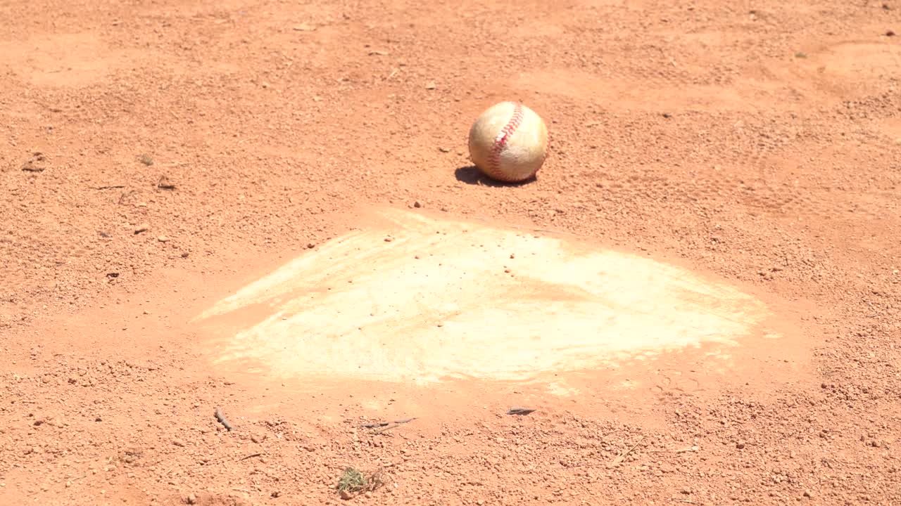 Premium stock video - Baseballs rolling across home plate