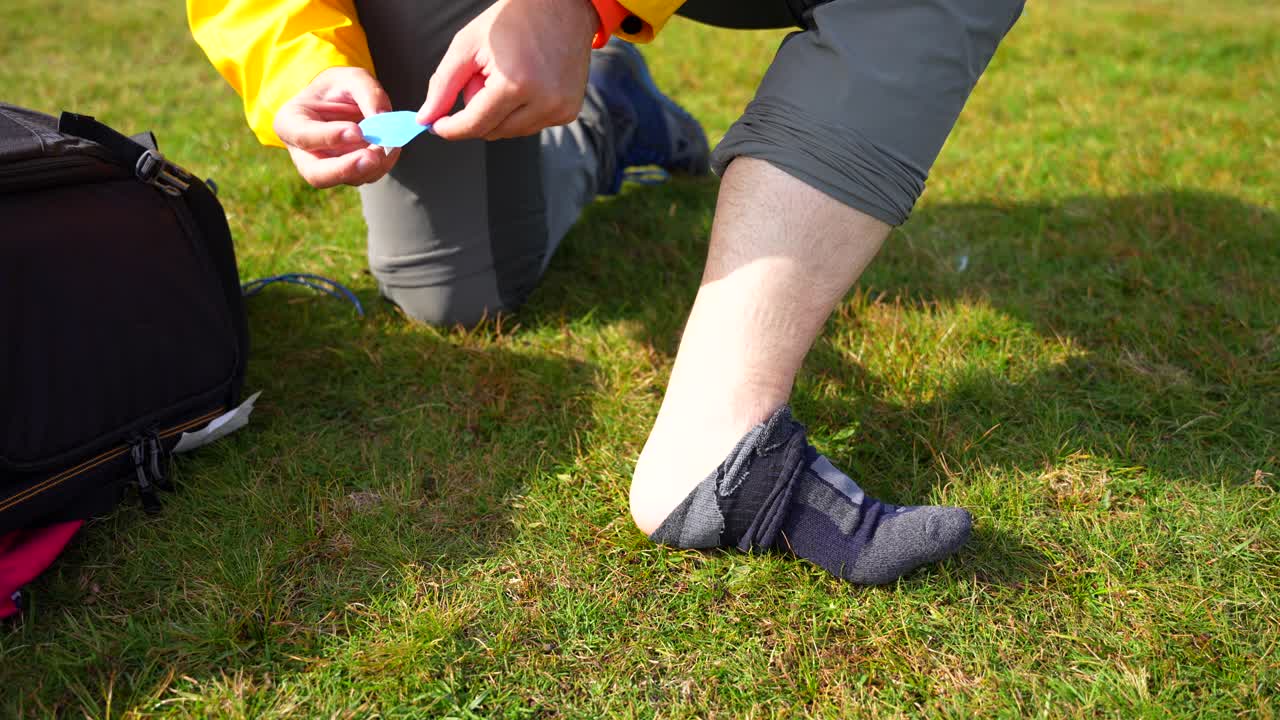 Premium stock video - Hiker takes off sock to put adhesive pad to ...