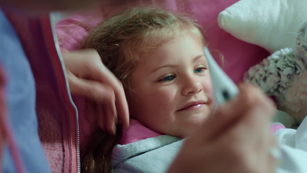 Premium stock video - Mother caring for sick child lying in bed with flu measuring temperature ...