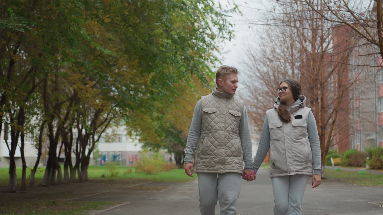 Evening stroll of young couple holding hands in matching outfits ...