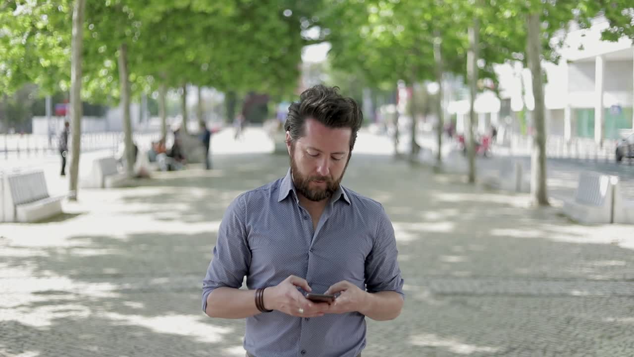 Premium stock video - Man walking on street and using smartphone