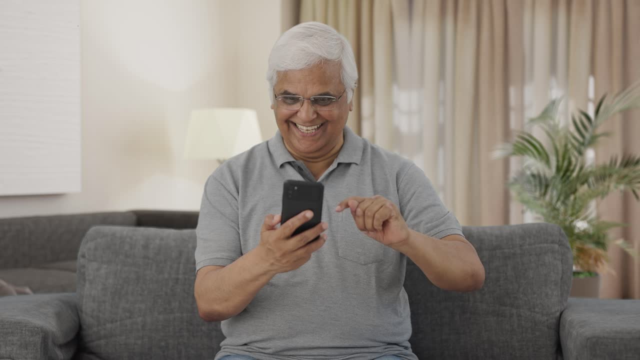 Happy indian old man scrolling through phone Premium Stock Video Footage