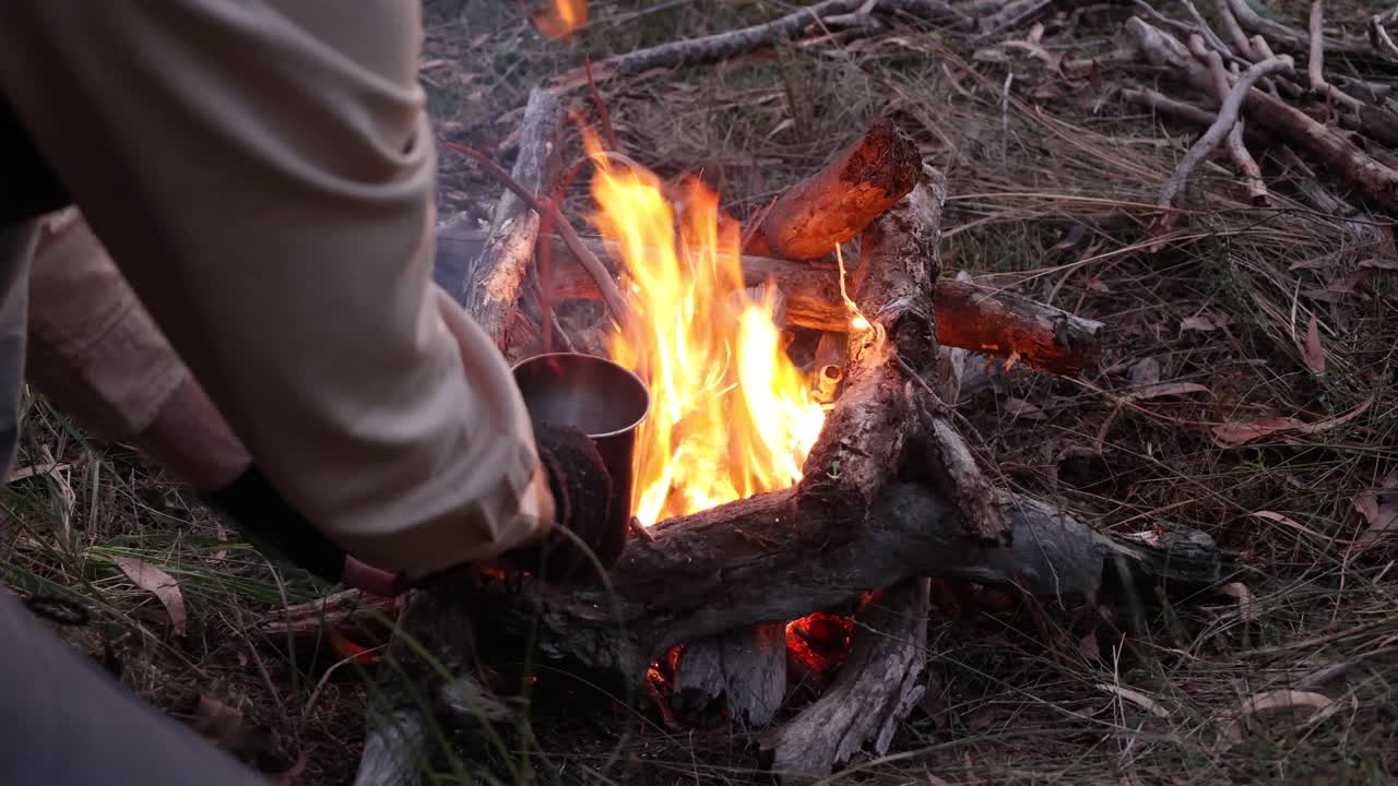 A Close Up Shot Of A Bushan Placing A Pot On A Campfire Out In The ...