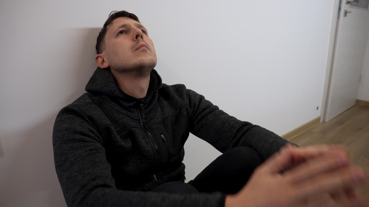 Man sitting on floor, showing deep worry and emotional distress ...