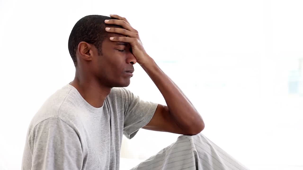 Premium stock video - Hungover man sitting on his bed