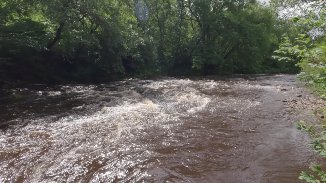 Static shot showing a flooded river creating dangerously fast currents ...