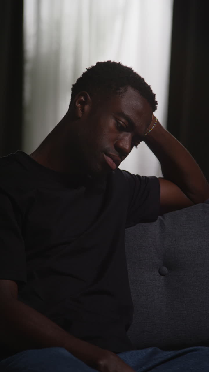 Vertical Video Of Unhappy And Depressed Young Man Sitting On Sofa At ...