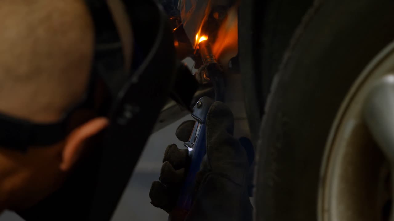 Premium stock video - Mechanic using wielding torch on a car 4k