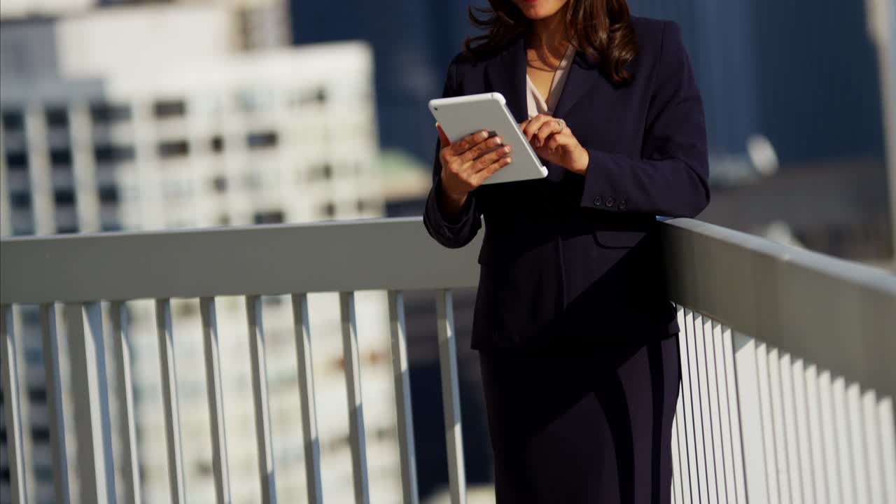 Hispanic female manager using touchscreen technology on rooftop ...