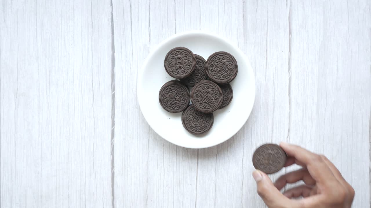 Hand holding an Oreo cookie from a plate of Oreos | Premium Stock Video ...