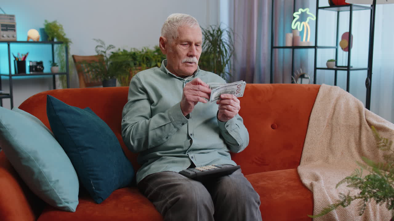 Rich grandfather old man counting money cash and use calculator ...