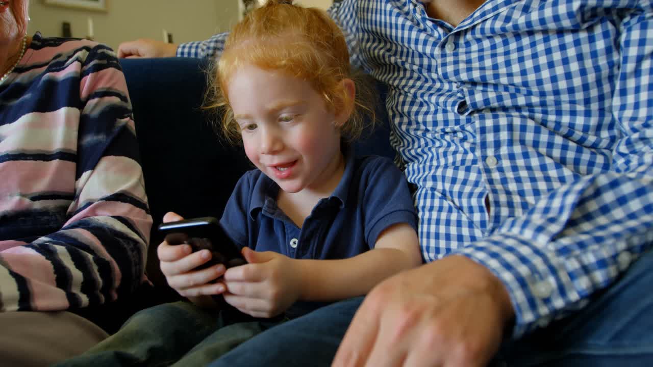 Premium stock video - Family using mobile phone in living room 4k