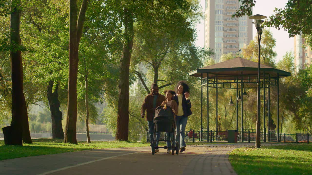 Premium stock video - Happy family pushing stroller walking green alley ...
