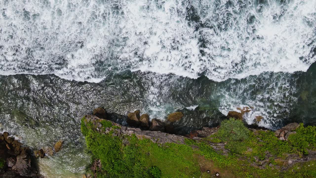 Overhead drone shot of Big waves hitting the rocky shore cliffs ...