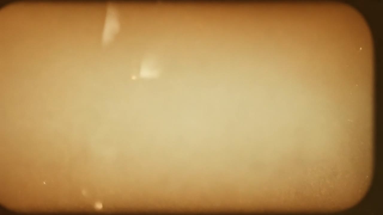 Light projects through a vintage film projector, revealing floating ...