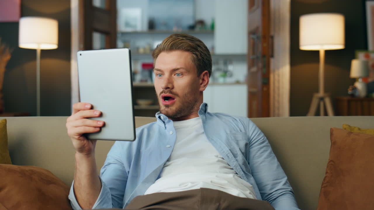 Surprised man reading tablet screen at house closeup. wondering guy ...