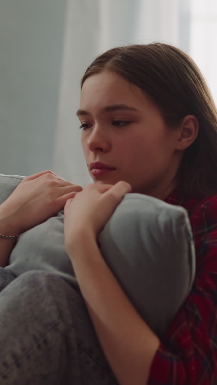 Pensive lady cries hugging grey pillow on sofa in living room zoom in ...