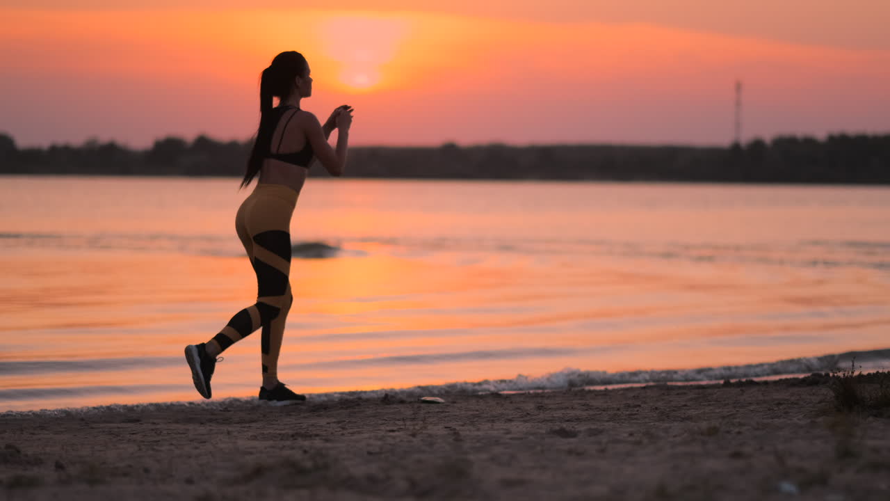 Premium stock video - A woman performs sit-ups at sunset on the beach ...