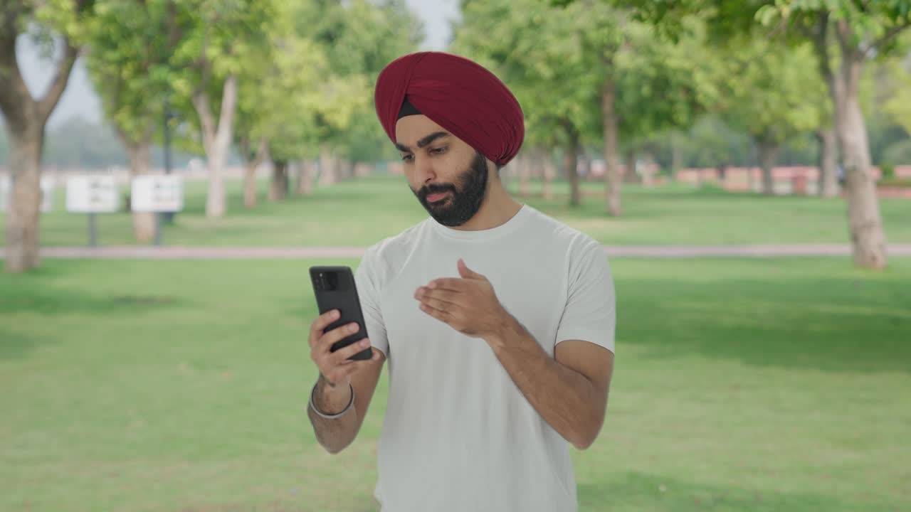 Premium stock video - Angry sikh indian man talking on video call in park