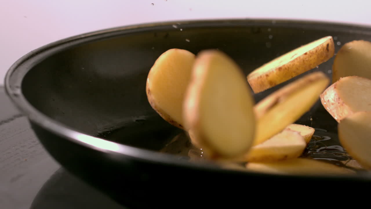 Potato wedges falling in a hot pan Premium Stock Video Footage