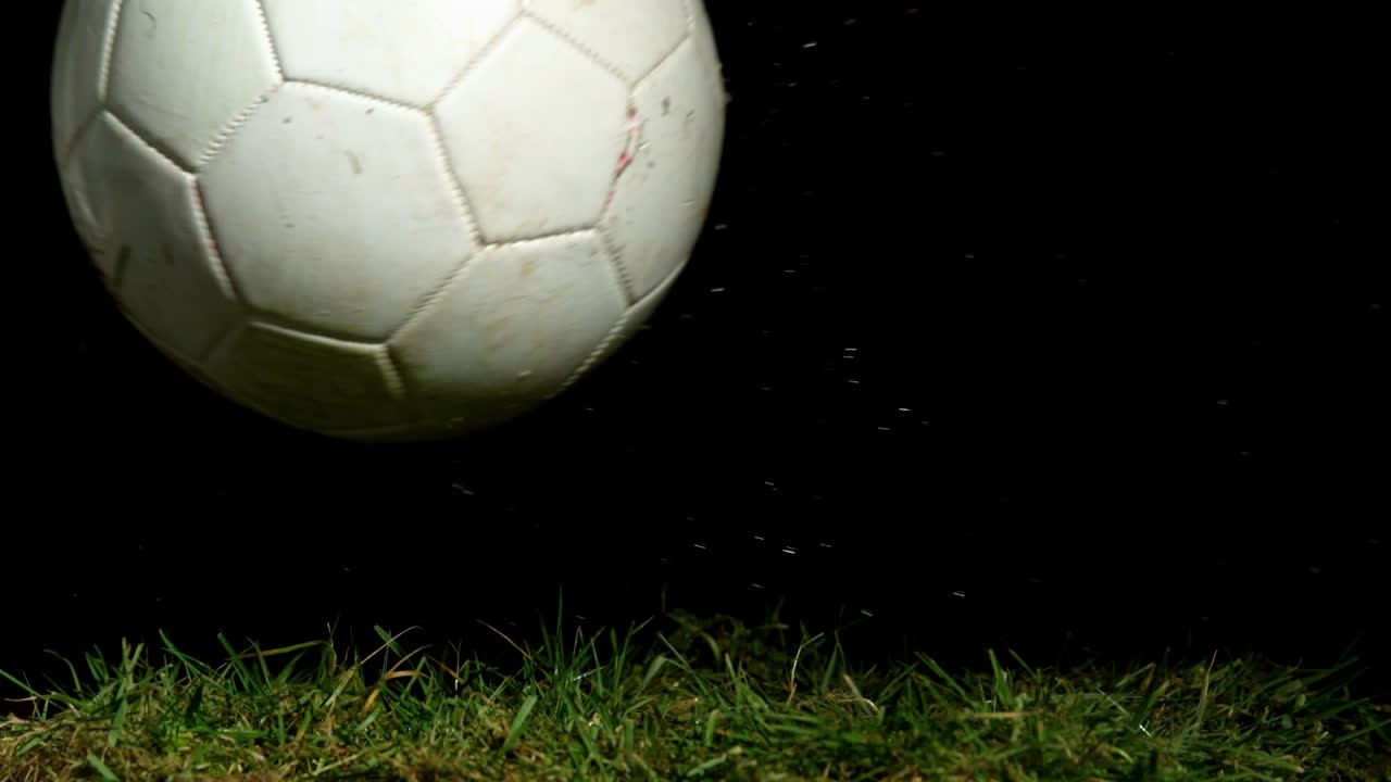 Premium stock video - Dirty football rolling on grass