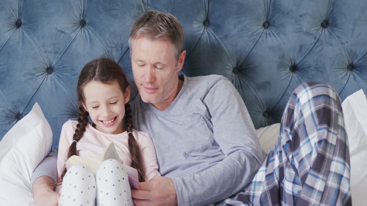 Premium stock video - Father and daughter reading a book together 4k