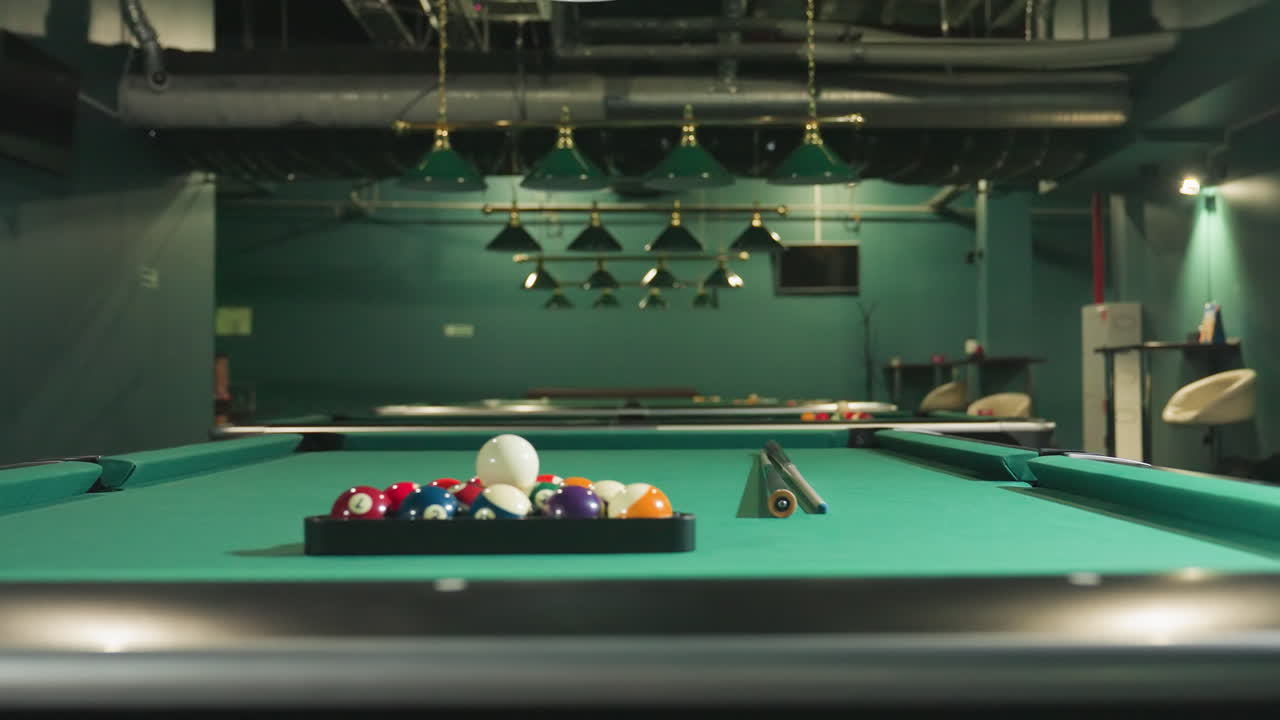 Shot of green pool tables with billiard balls arranged on them and cue ...