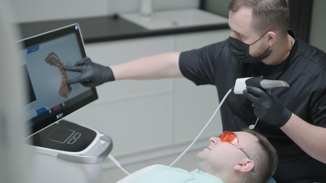 Doctor scans the patient's teeth in the clinic. The dentist holds in ...
