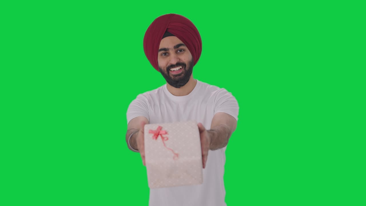 Premium stock video - Happy sikh indian man giving a gift green screen